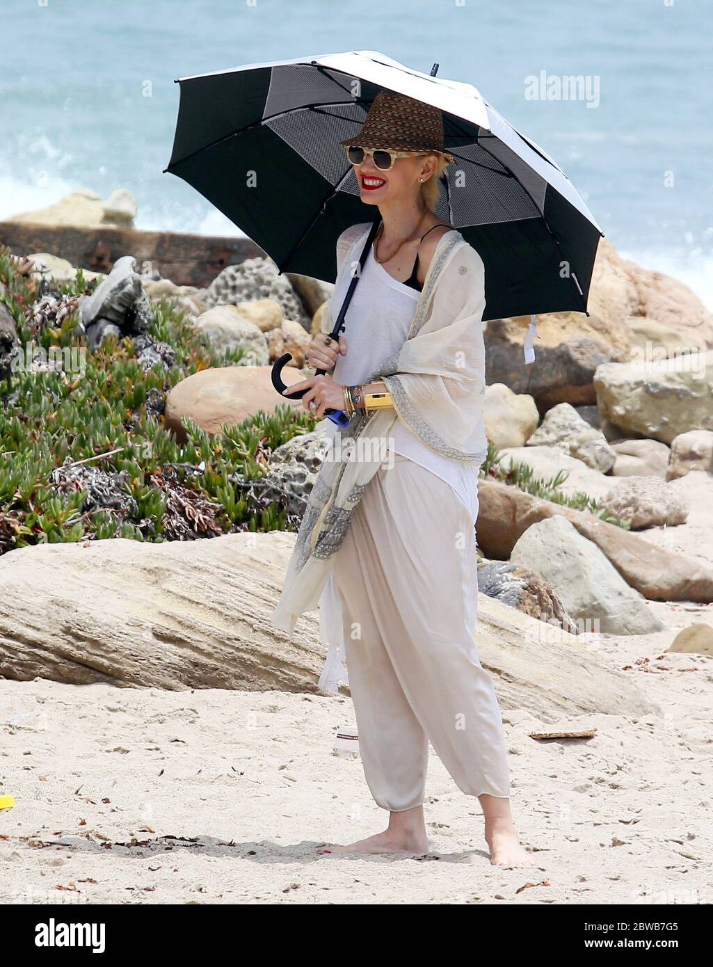 Gwen Stefani wearing hat, walking on beach with pet dog and her boys ...