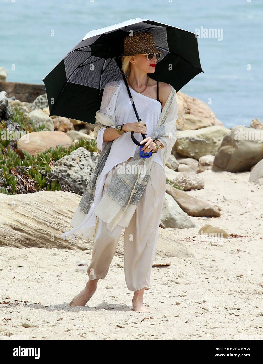 Gwen Stefani wearing hat, walking on beach with pet dog and her boys ...
