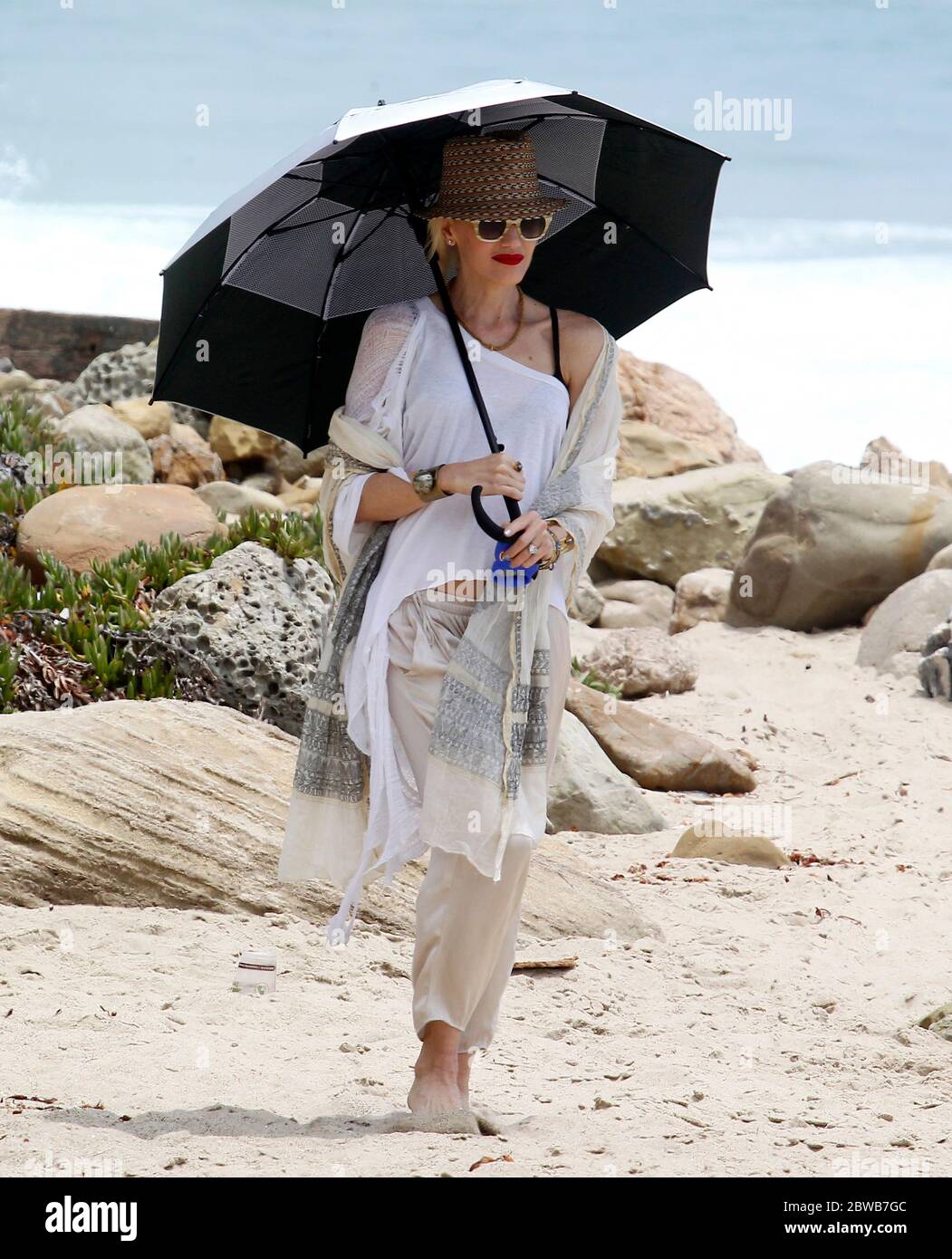 Gwen Stefani wearing hat, walking on beach with pet dog and her boys ...