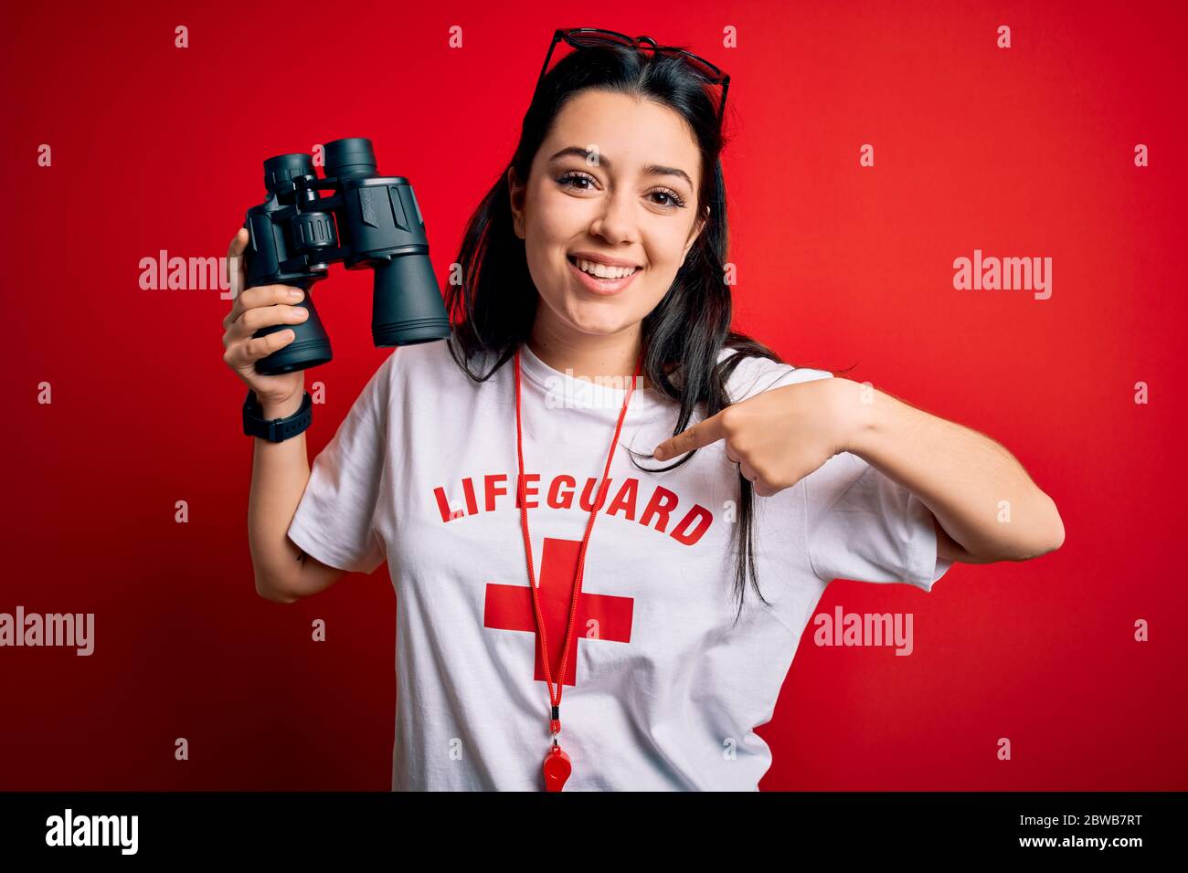 Young lifeguard woman wearing secury guard equipent holding binoculars ...