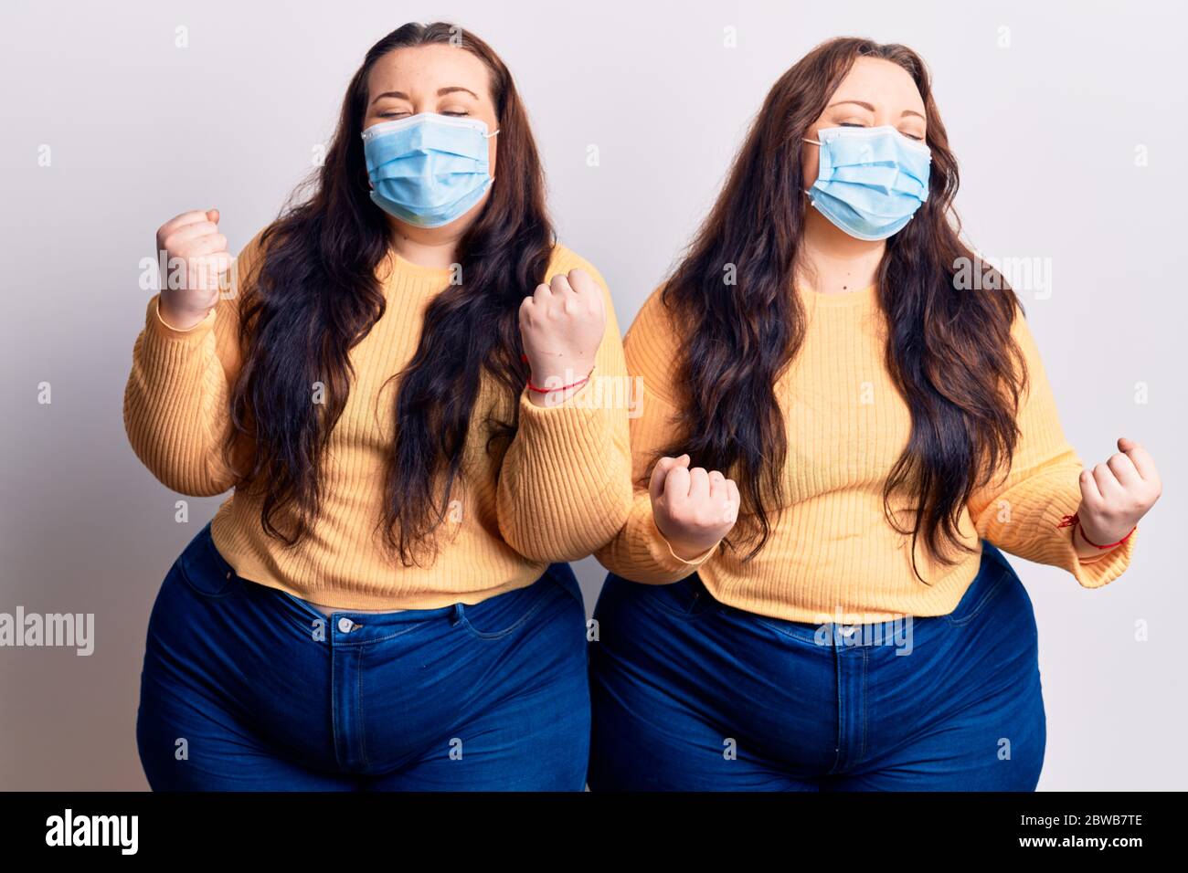 Young plus size twins wearing medical mask excited for success with ...