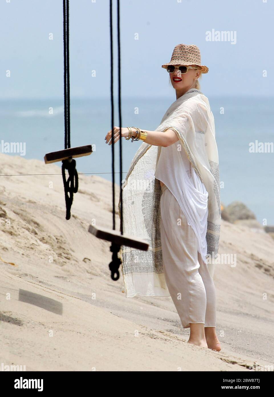 Gwen Stefani wearing hat, walking on beach with pet dog and her boys ...