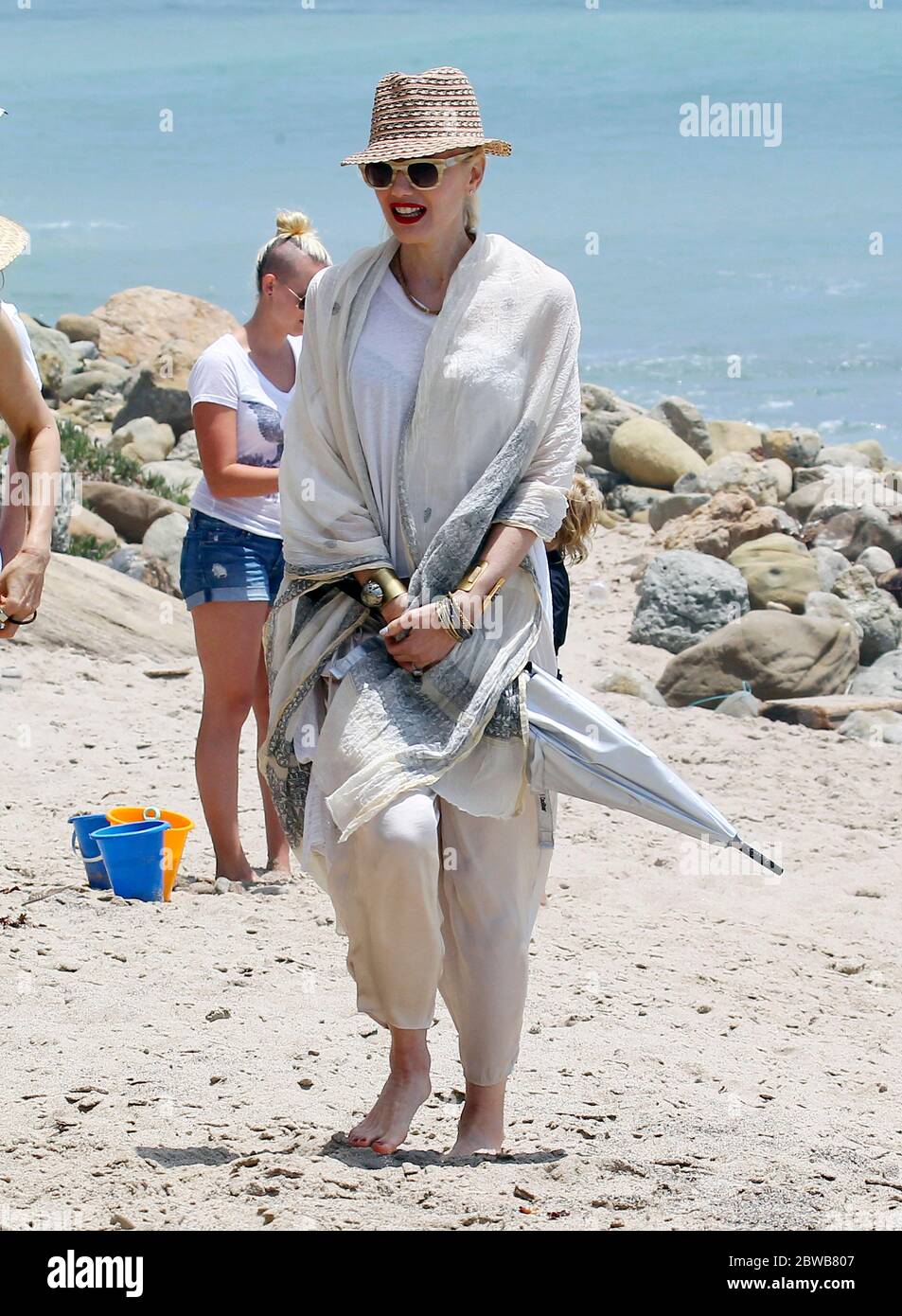 Gwen Stefani wearing hat, walking on beach with pet dog and her boys ...