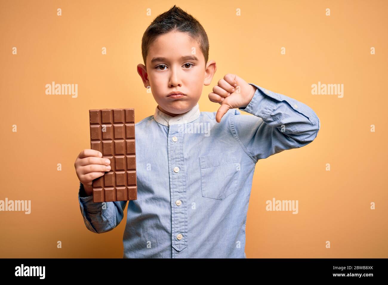 Young little boy kid eating sweet chocolate bar for dessert over ...