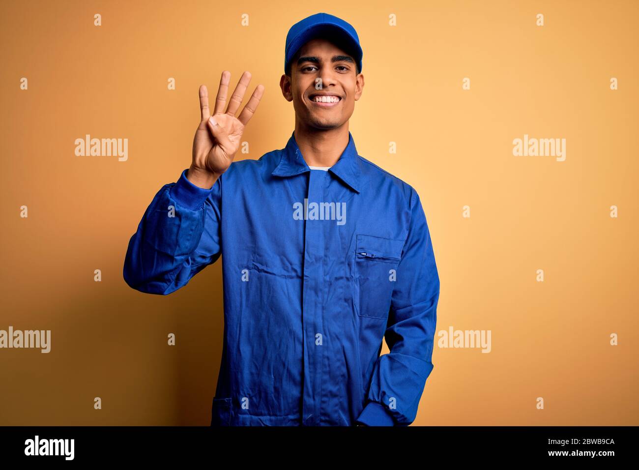 Young african american mechanic man wearing blue uniform and cap over ...