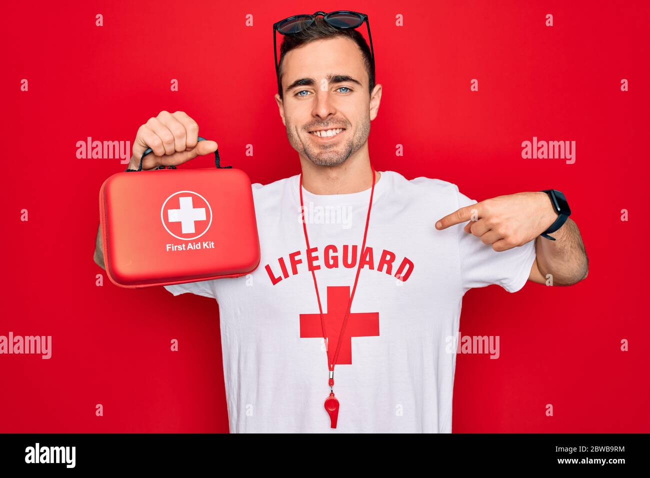 Young handsome lifeguard man wearing t-shirt with red cross and whistle ...