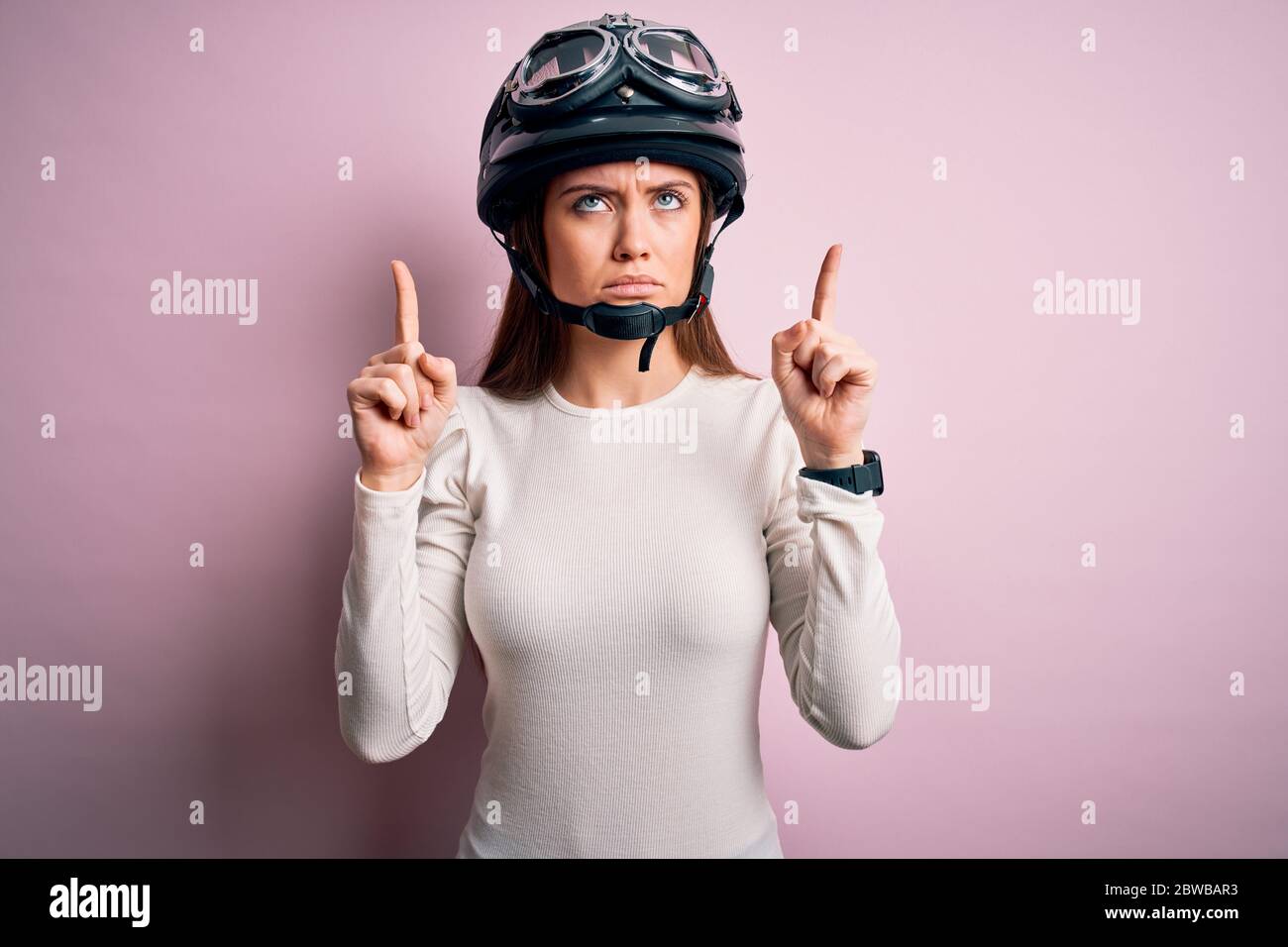 Young beautiful motorcyclist woman with blue eyes wearing moto helmet ...