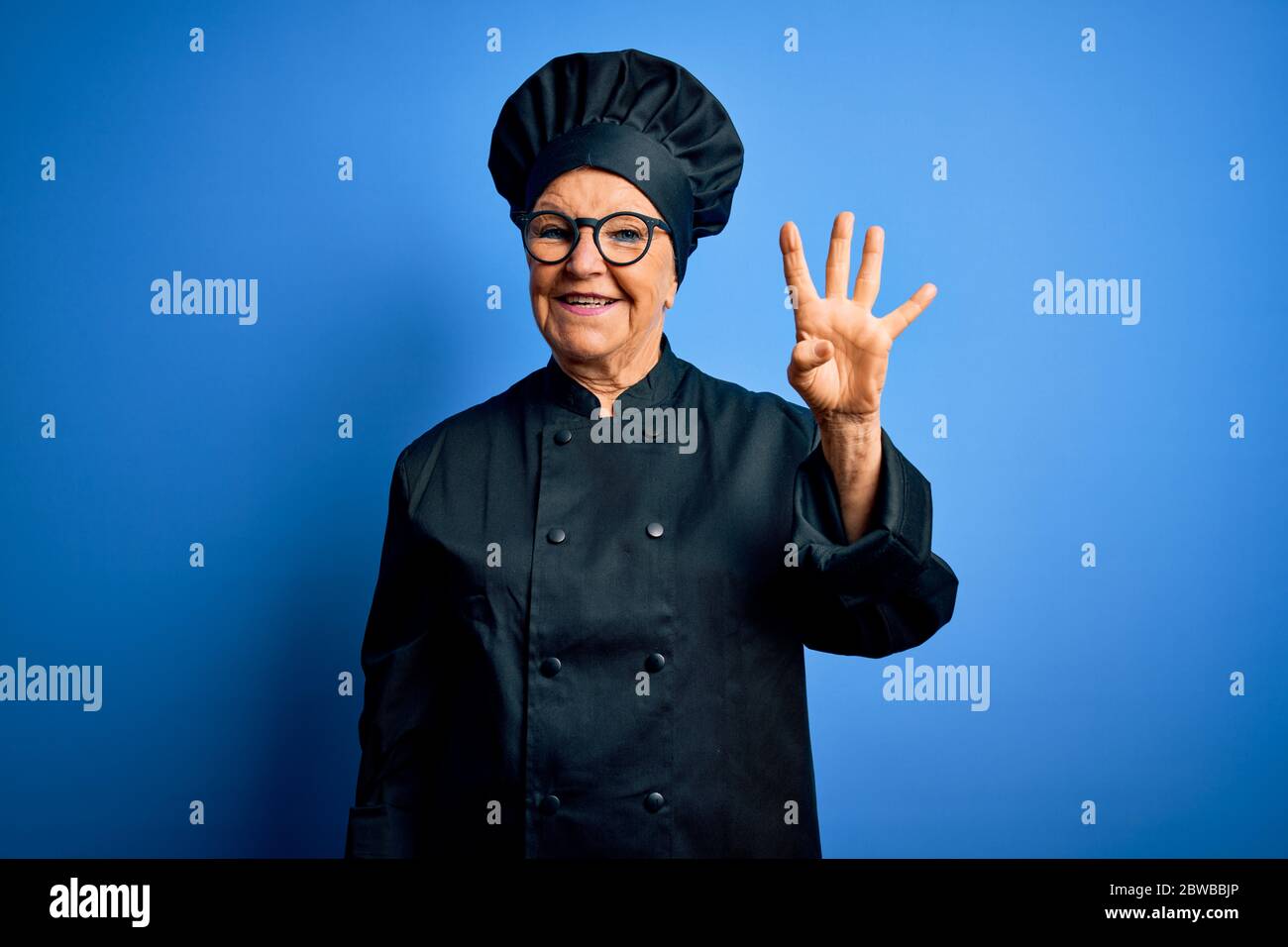 Senior beautiful grey-haired chef woman wearing cooker uniform and hat ...
