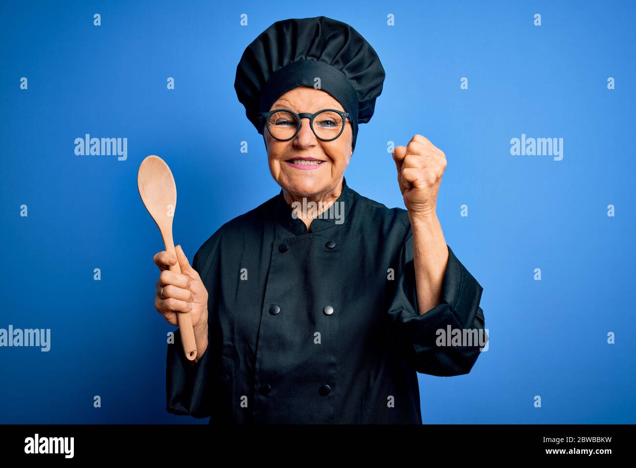 Senior beautiful grey-haired chef woman wearing cooker uniform and hat ...