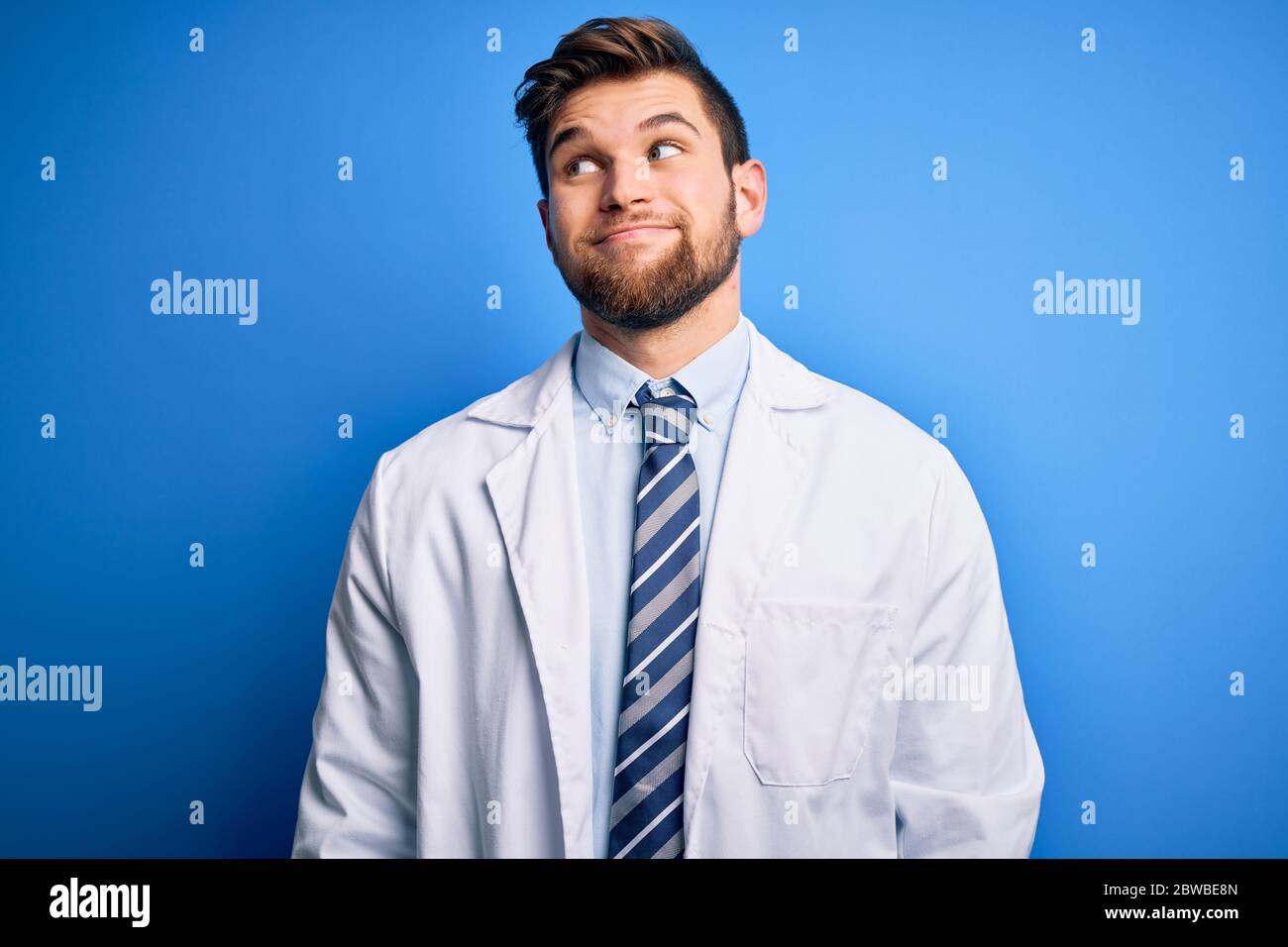 Young blond therapist man with beard and blue eyes wearing coat and tie ...
