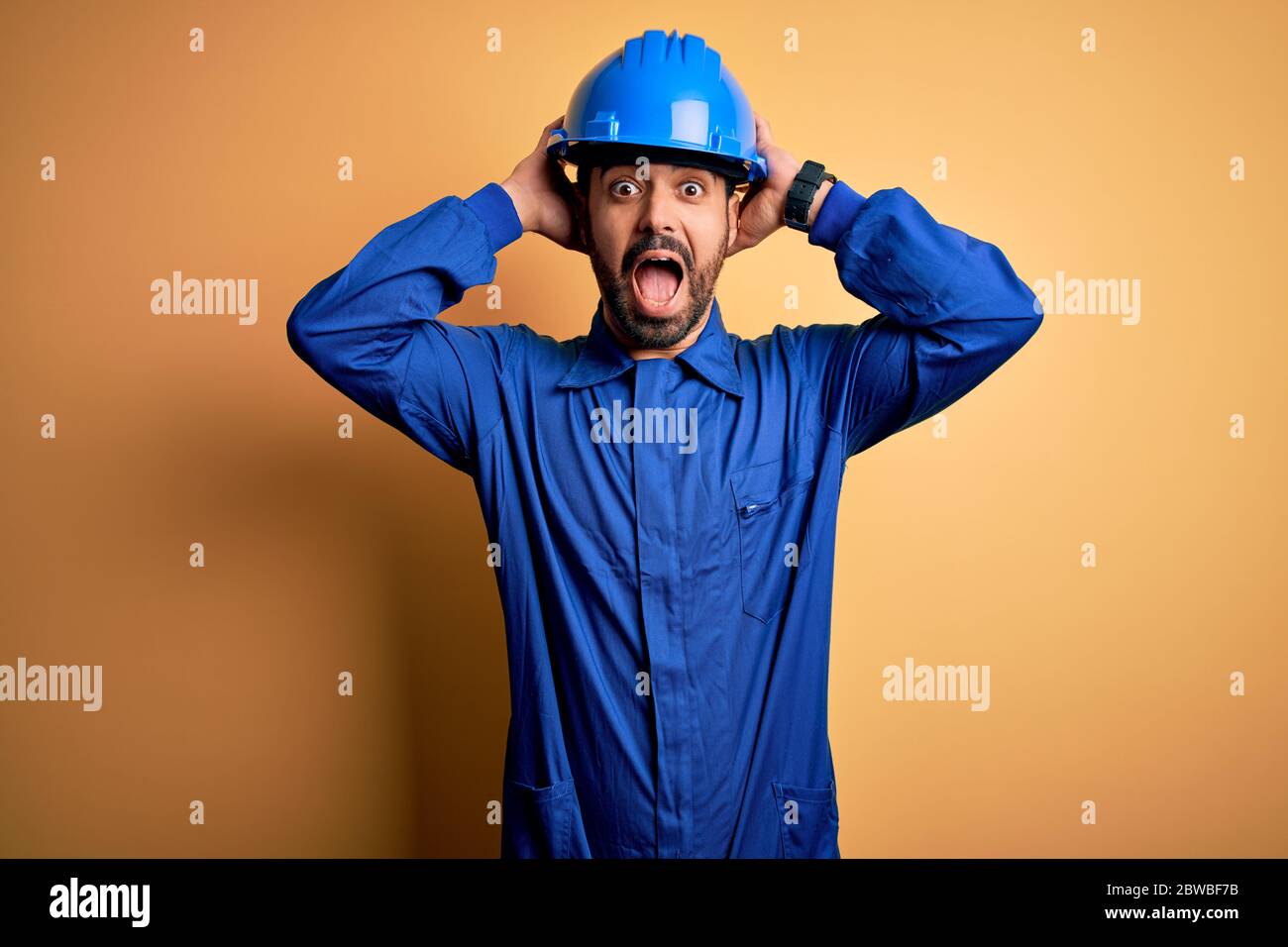 Mechanic man with beard wearing blue uniform and safety helmet over ...