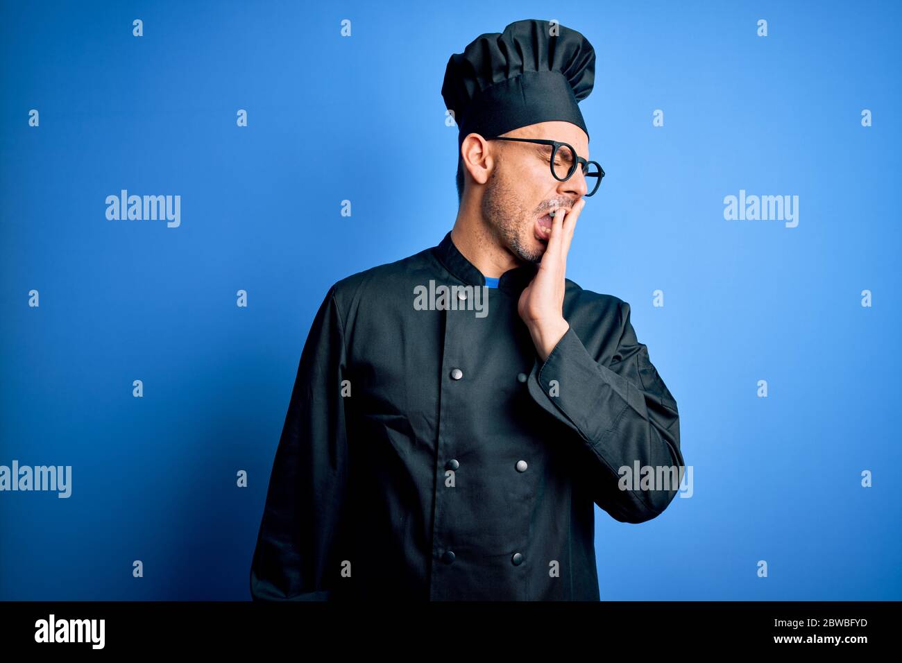Young handsome chef man wearing cooker uniform and hat over isolated ...