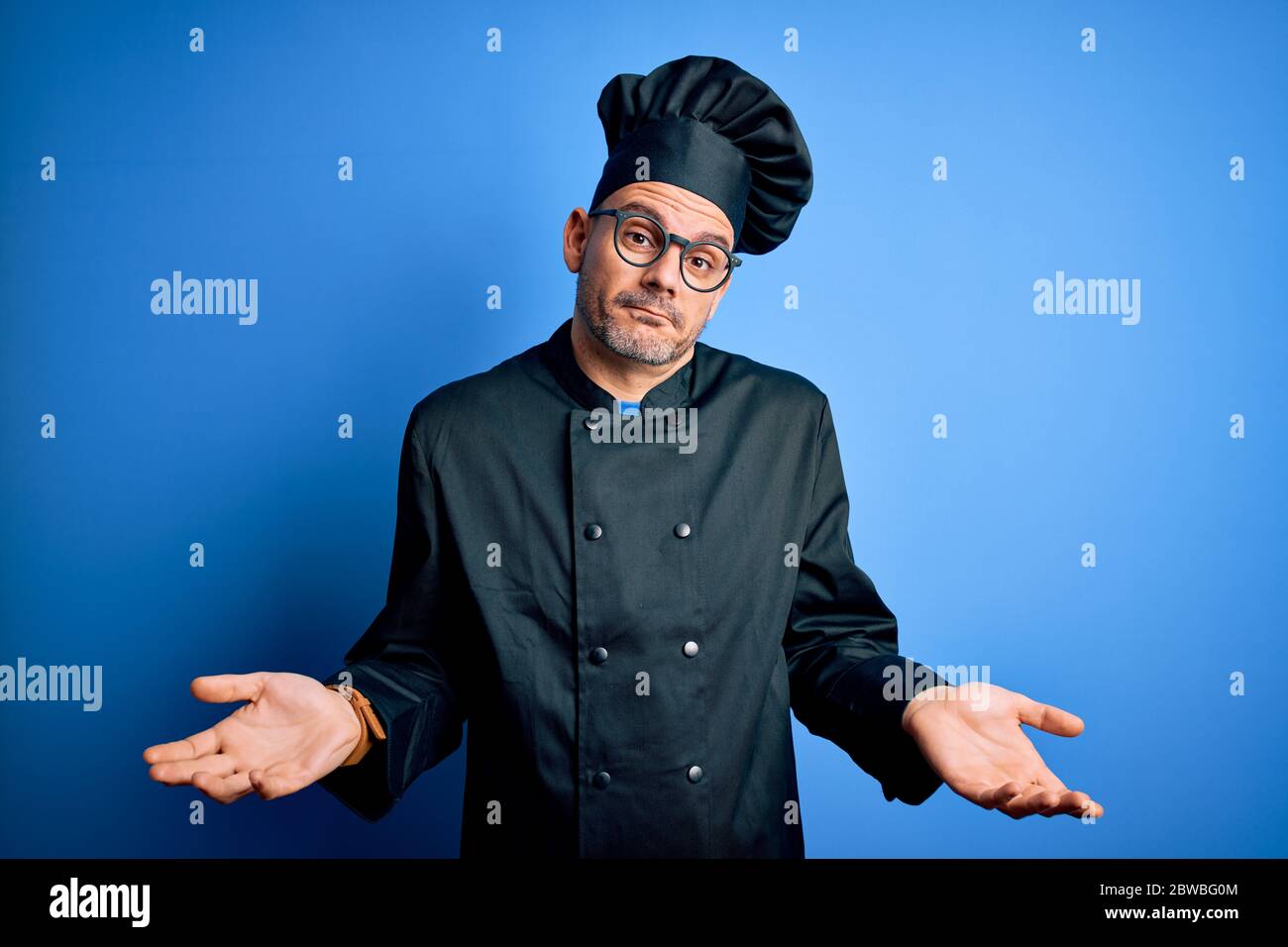 Young handsome chef man wearing cooker uniform and hat over isolated ...