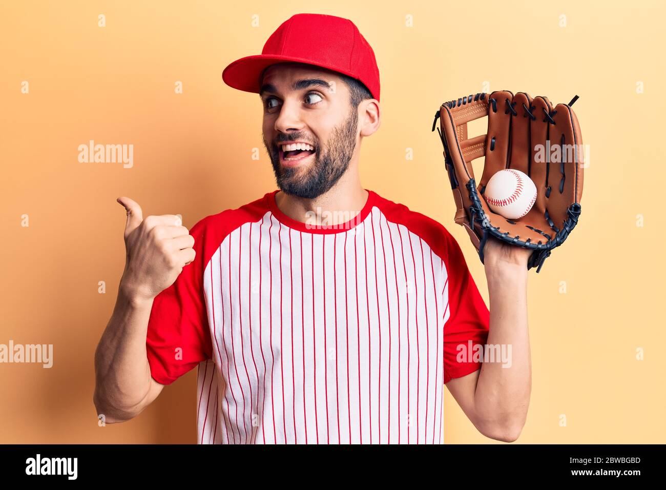 Young handsome man with beard playing baseball using ball and glove ...