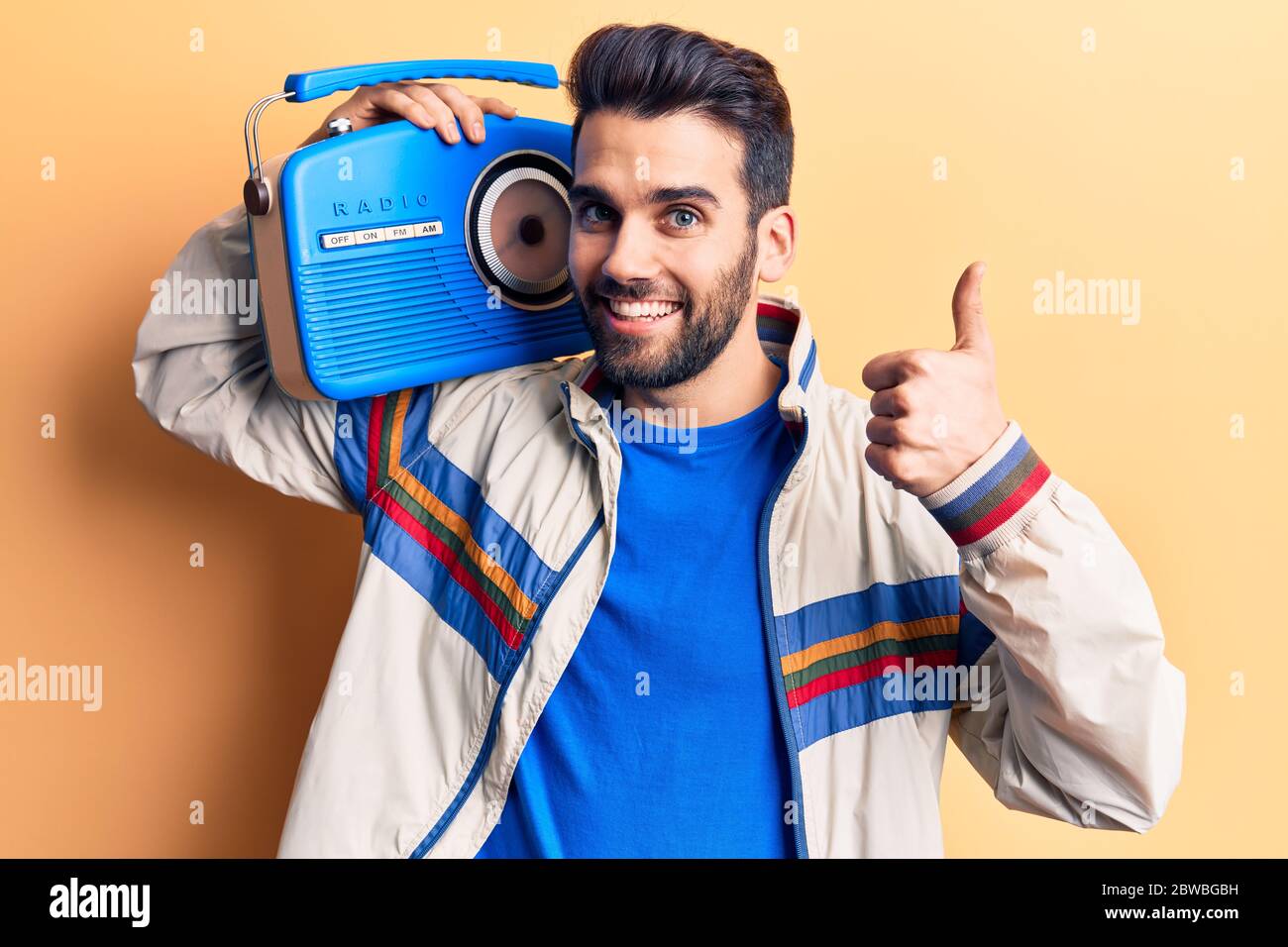 Young handsome man with beard listening to music using vintage boombox ...
