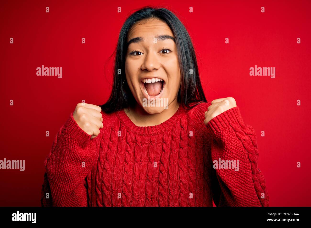 Young beautiful asian woman wearing casual sweater standing over ...
