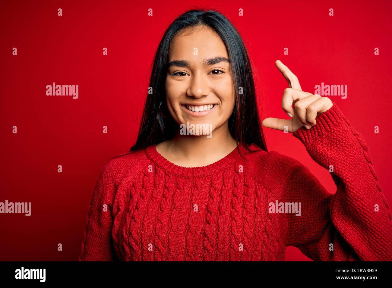 Young beautiful asian woman wearing casual sweater standing over ...