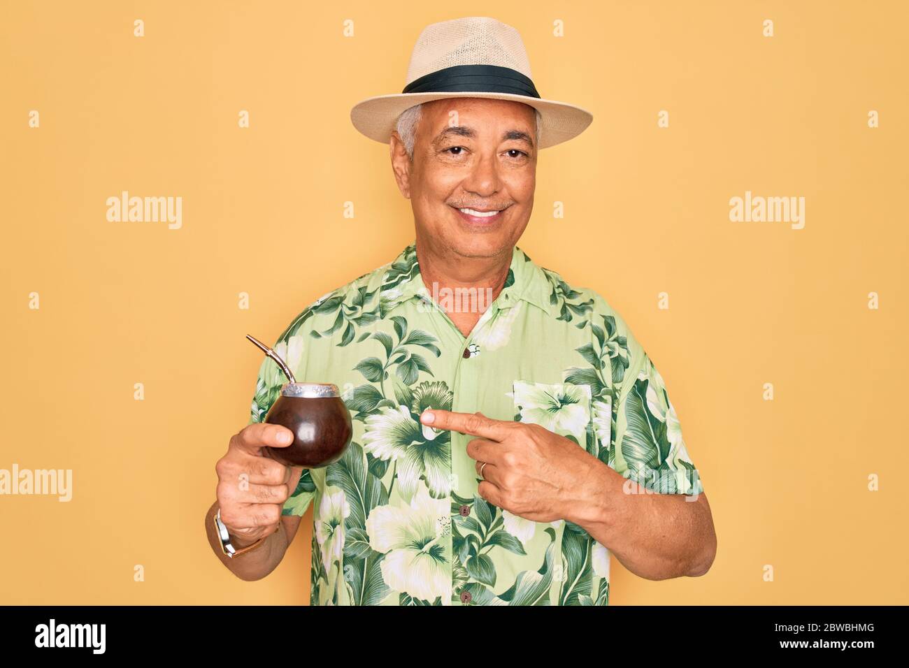 Middle age senior grey-haired man wearing summer hat drinking ...