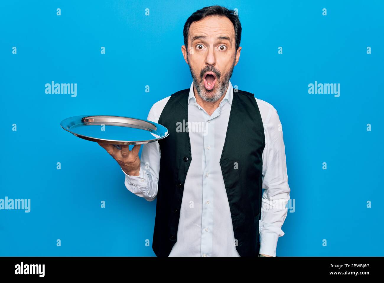 Middle age handsome waitress man holding tray standing over isolated ...