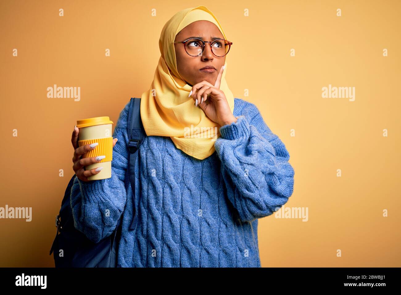 Young African American afro student woman wearing muslim hijab and glasses drinking coffee ...