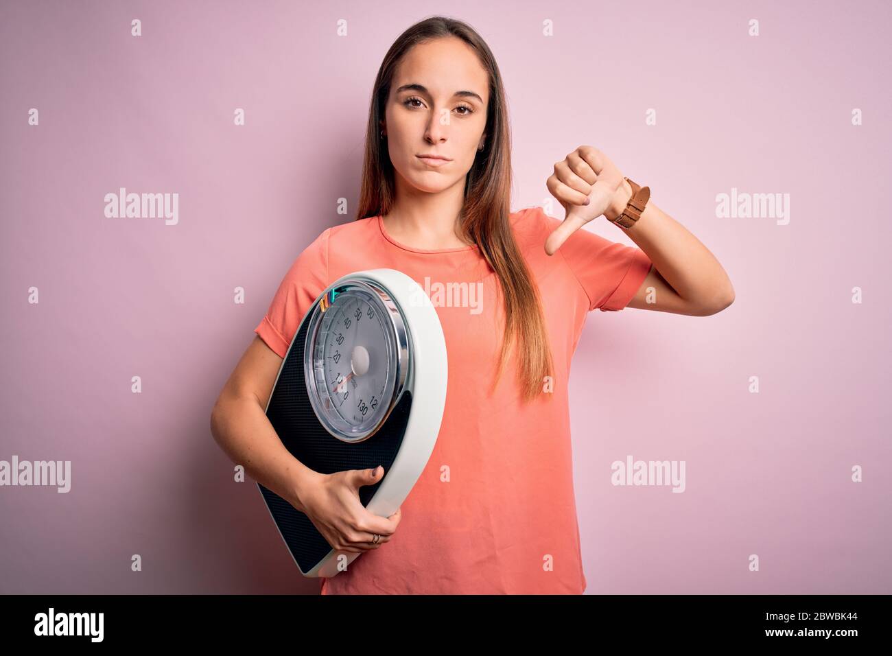Young beautiful woman controlling weight holding weighting machine over ...