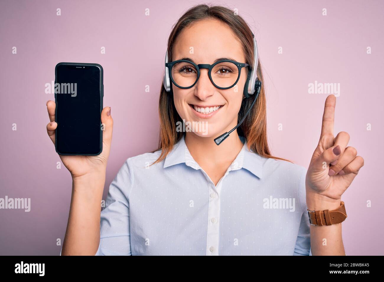 Beautiful call center agent woman working using headset holding ...