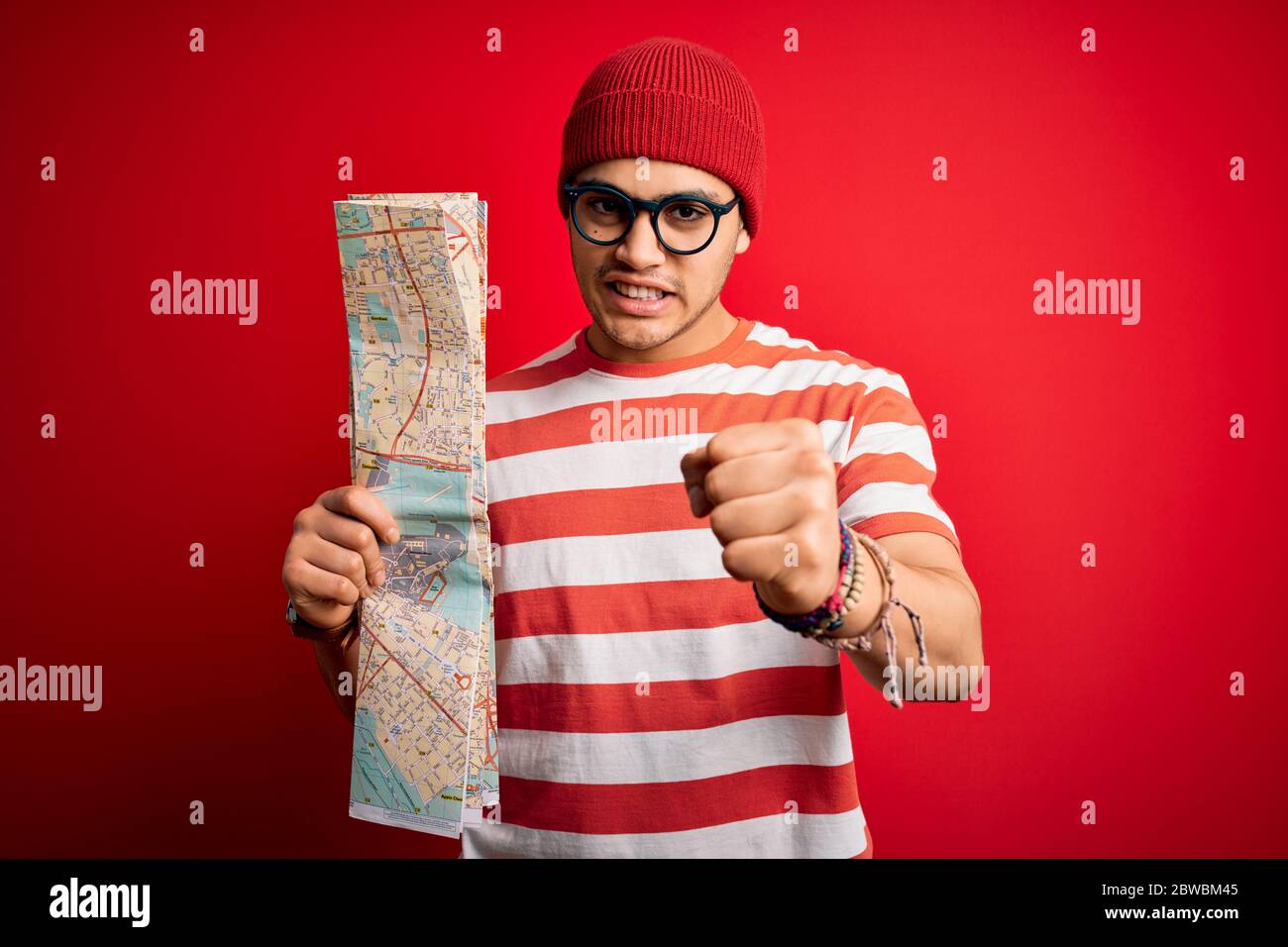 Young brazilian tourist man on vacation holding city map over isolated ...