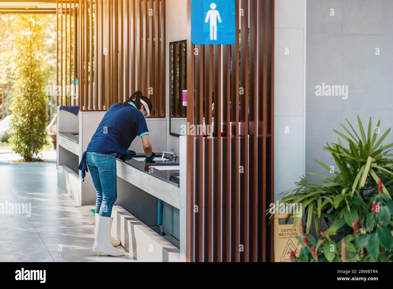 Female janitor using fabric and a detergent cleaning sink and tap in ...