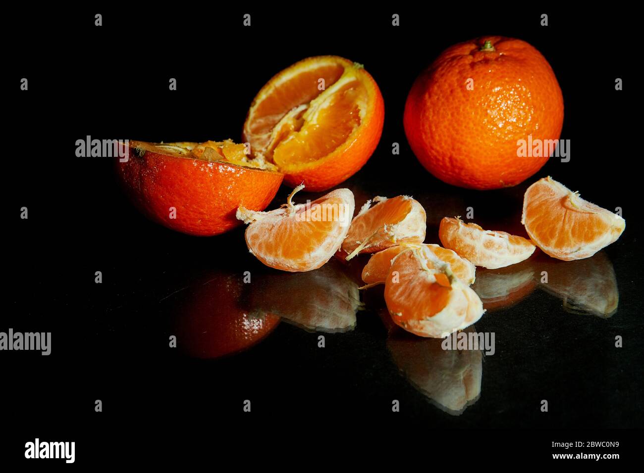 a few Mandarin in the cut with slices on a black background Stock Photo ...