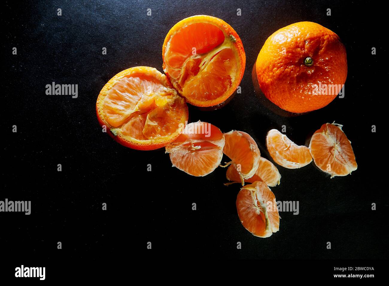 a few Mandarin in the cut with slices on a black background Stock Photo ...