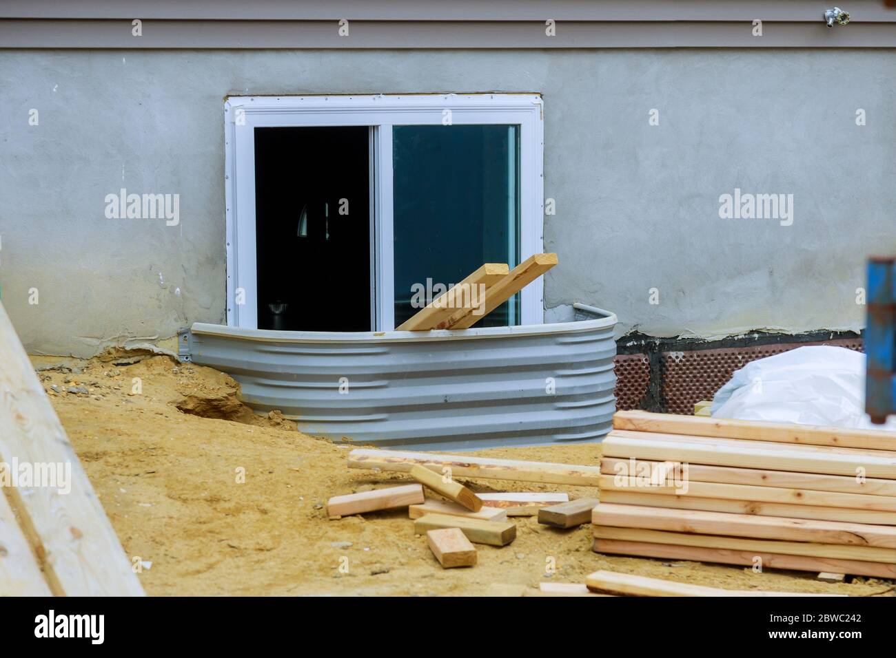 Stack of unloading wooden beams on window well on basement construction ...