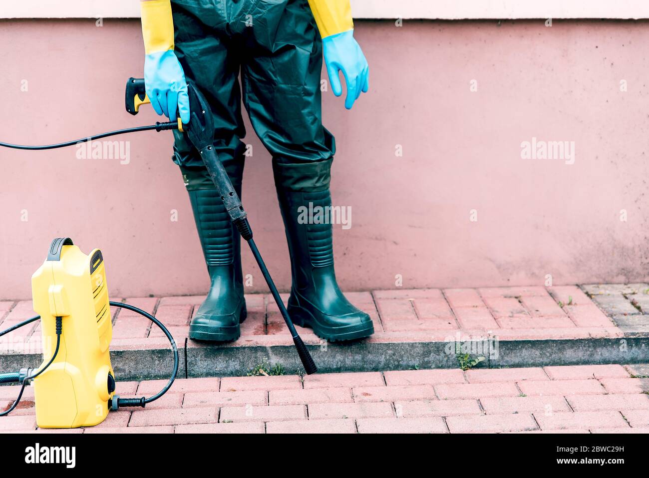 Man cleaning red, conrete pavement block using high pressure water ...