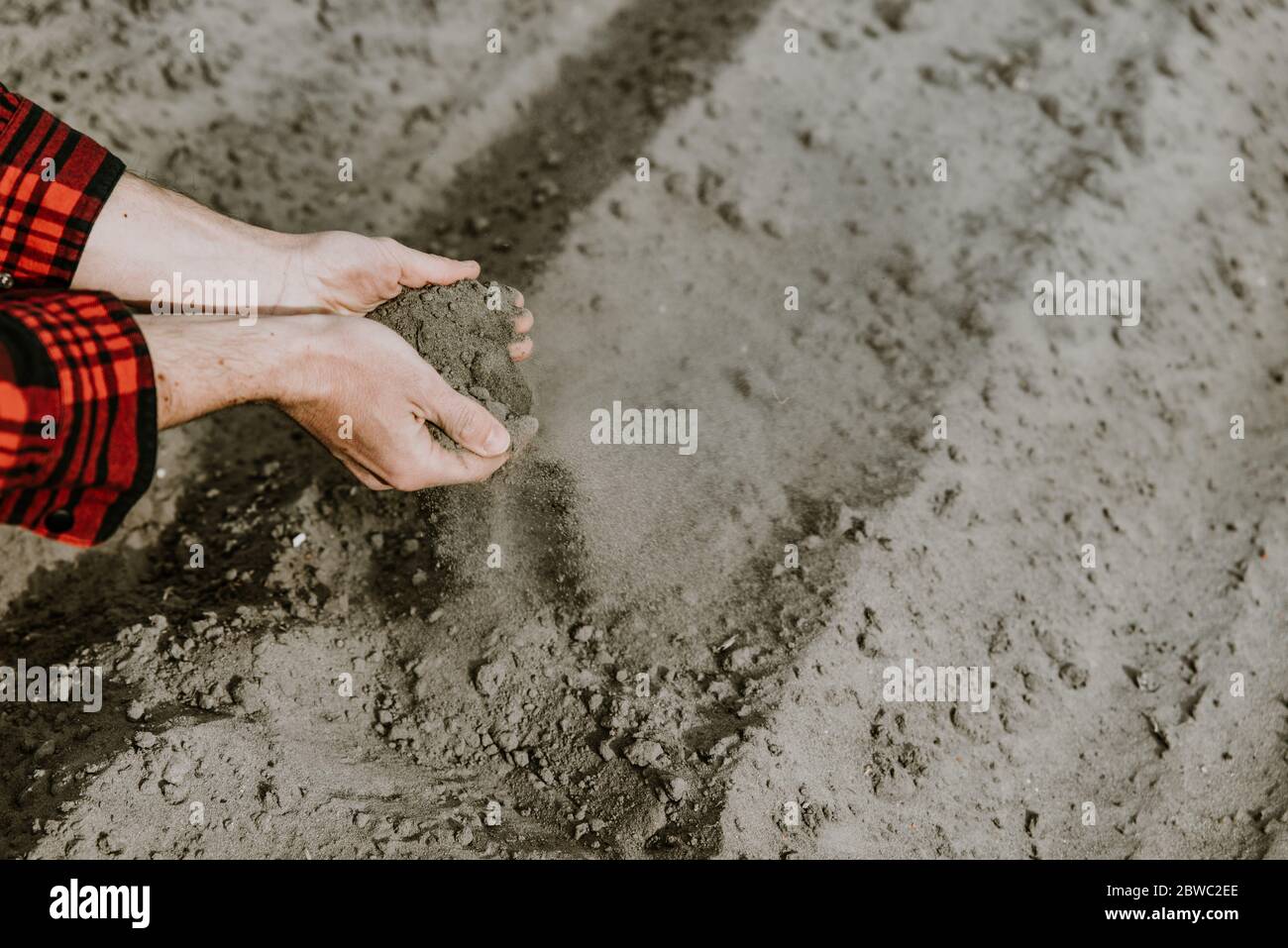 Cropped view of farmer hands holding sand, pouring dry sandy soil on ...