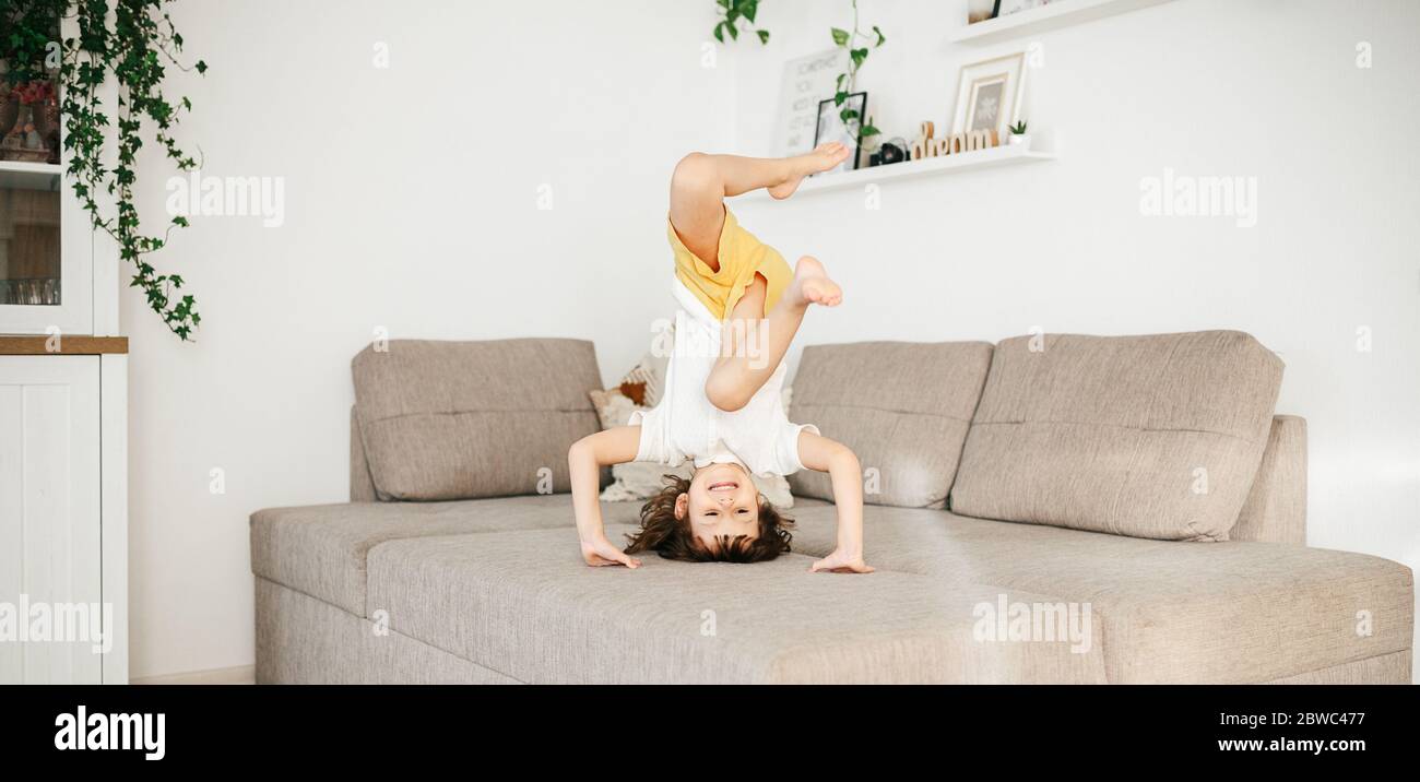 Cute little toddler girl tumbling on sofa at home. Child Learn To ...
