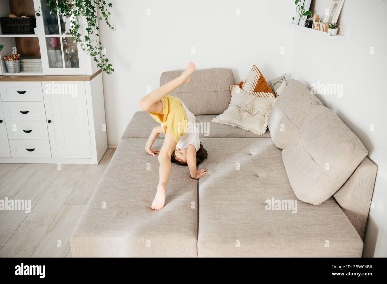 Cute little toddler girl tumbling on sofa at home. Child Learn To ...