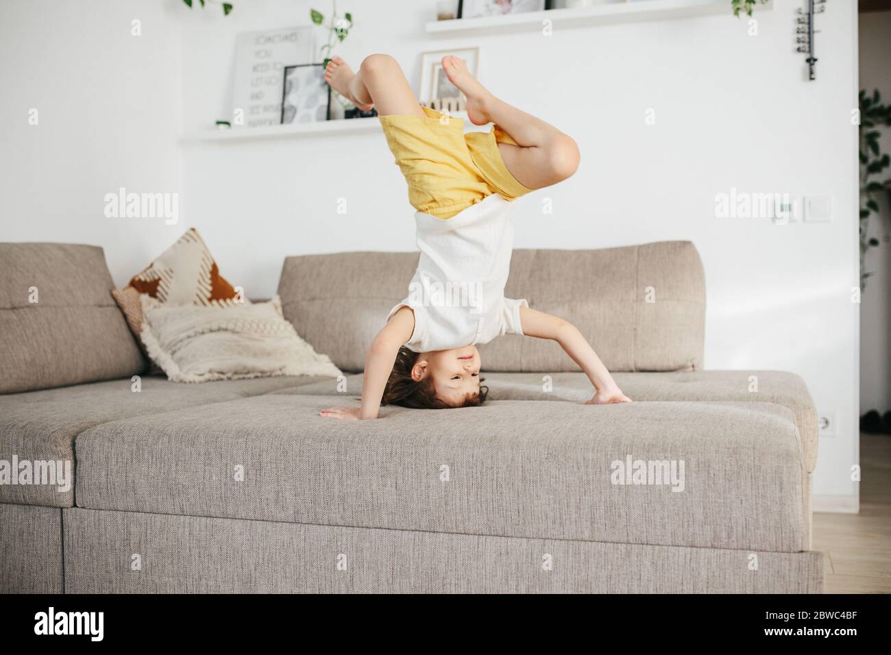 Beautiful little toddler tumbling on sofa at home. Child Learn To ...