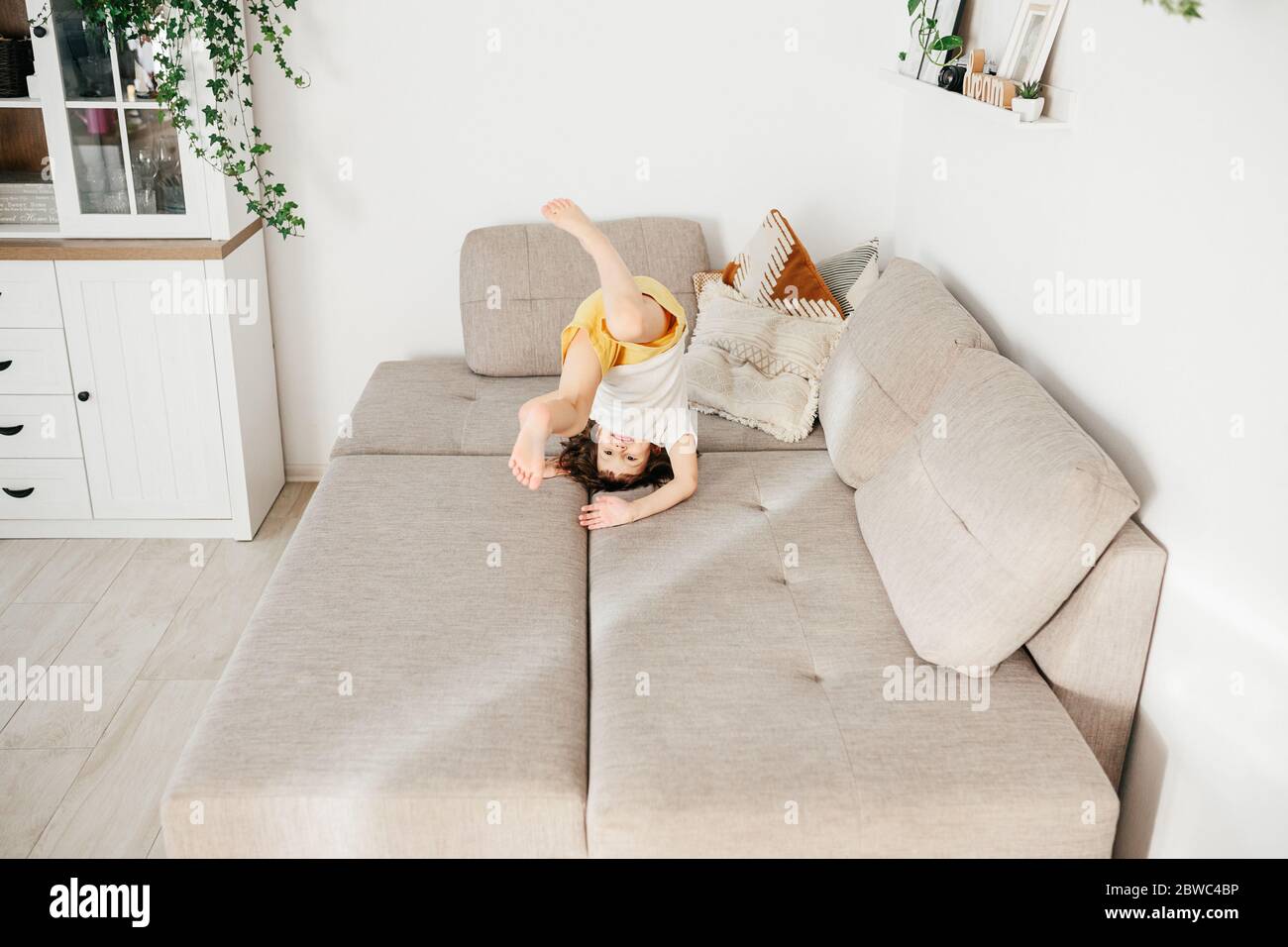 Cute little toddler girl tumbling on sofa at home. Child Learn To ...