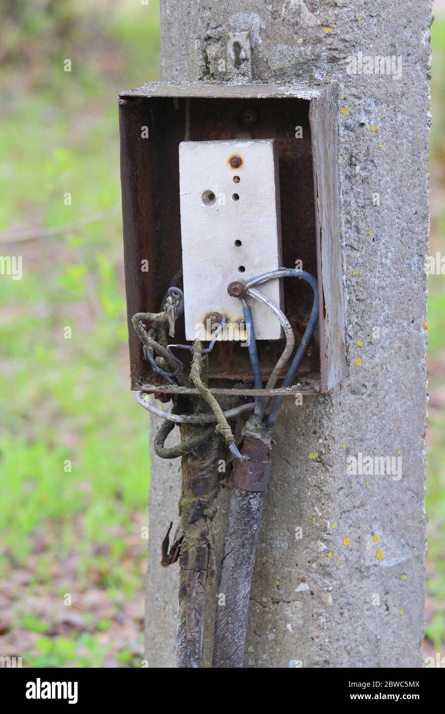 Iron old broken open distribution electric box on a concrete pole. The ...