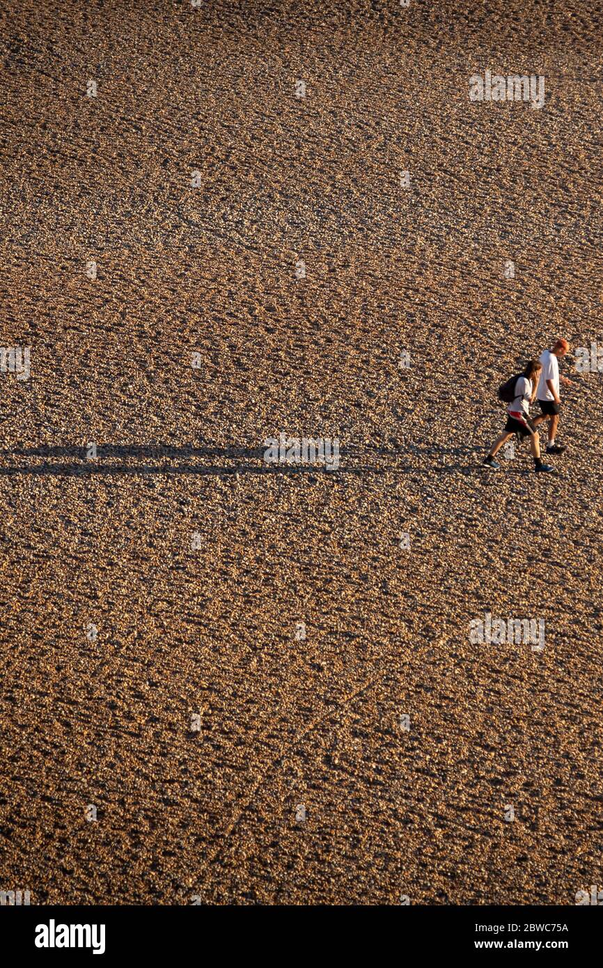 lone couple and shadows on Brighton beach Stock Photo - Alamy