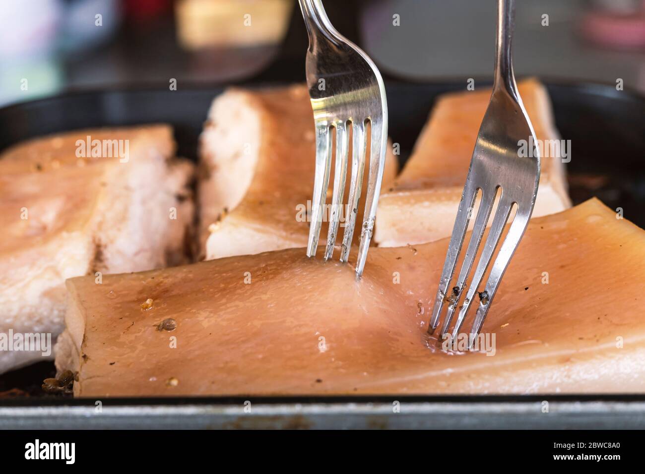 Posture while using a fork to pierce the pork skin for cooking Stock ...