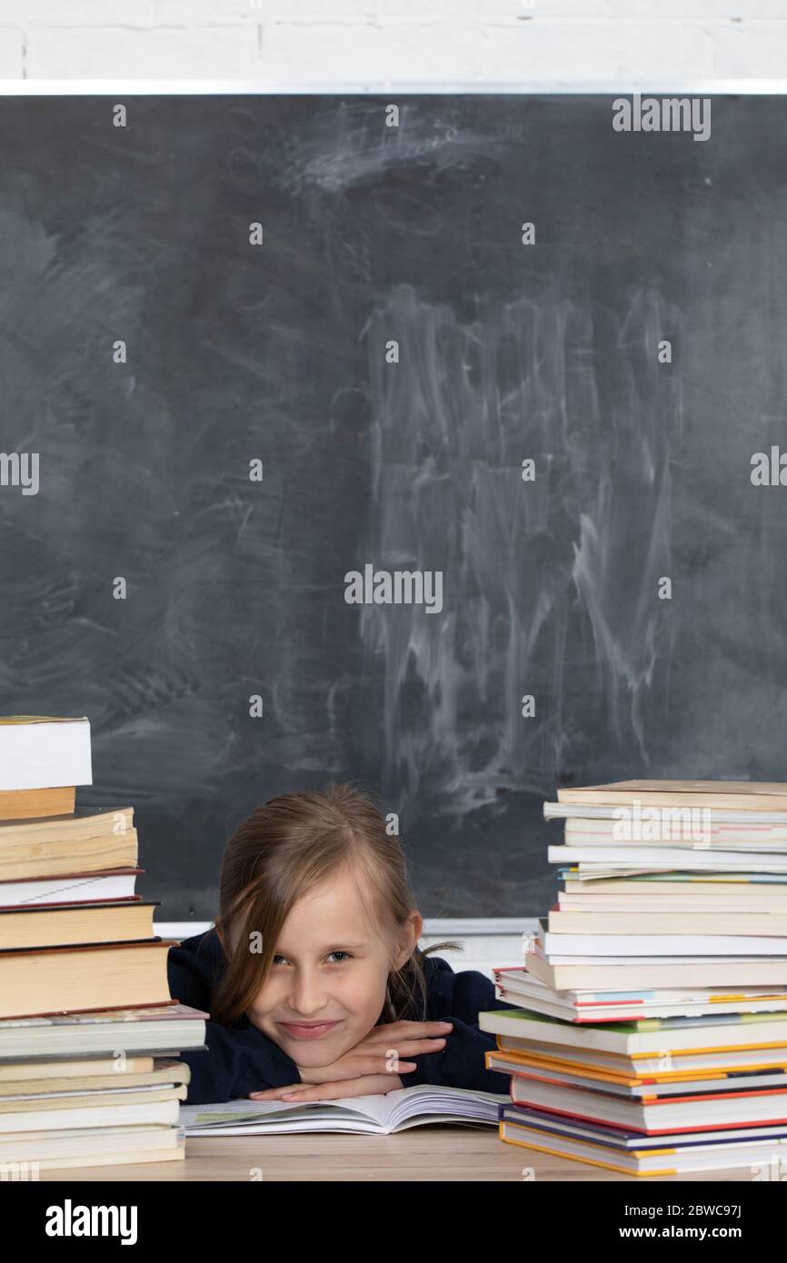 Younger schoolgirl. Stack of books and dictionaries and encyclopedias ...