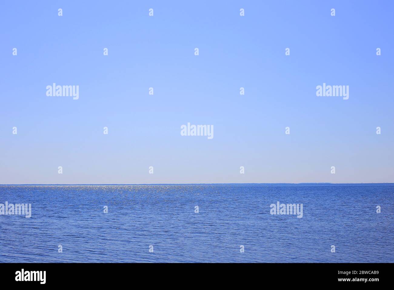 Calm sea water with blue sky on the horizon Stock Photo - Alamy