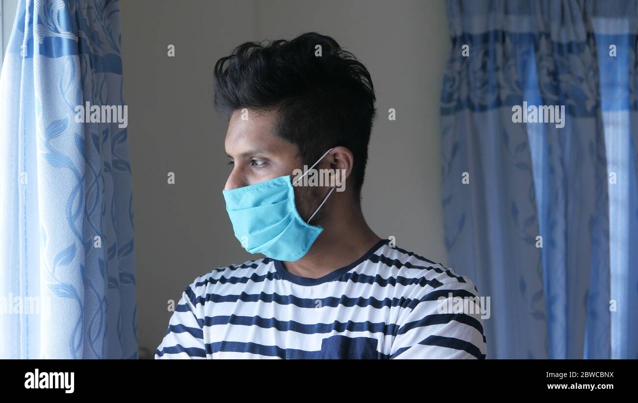 A young asian man mask on his face looking through window Stock Photo ...