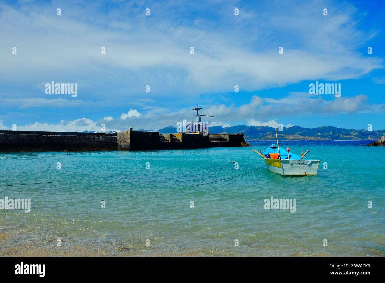 A small boat docked on a calm blue water seaport in Ivana Port, Batanes ...