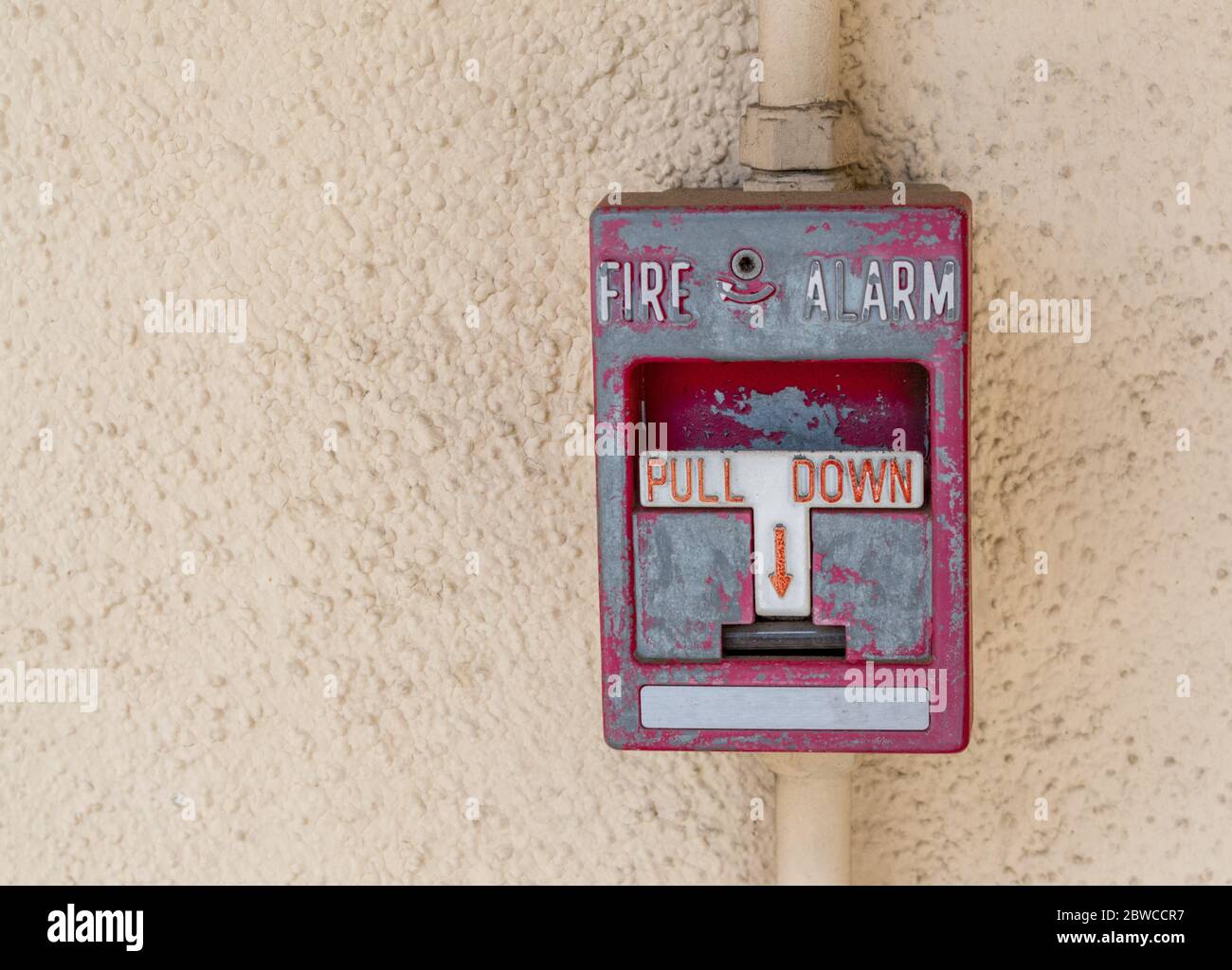 a neglected fire alarm box with peeling paint on an exterior wall with ...