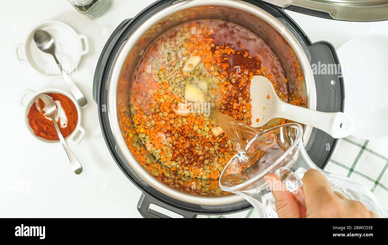 Multi cooker lentil soup recipe. Woman pouring water into pot, close up ...