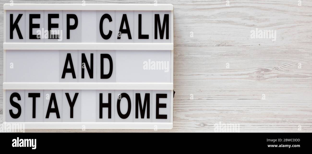 'Keep Calm and Stay Home' words on a lightbox on a white wooden ...