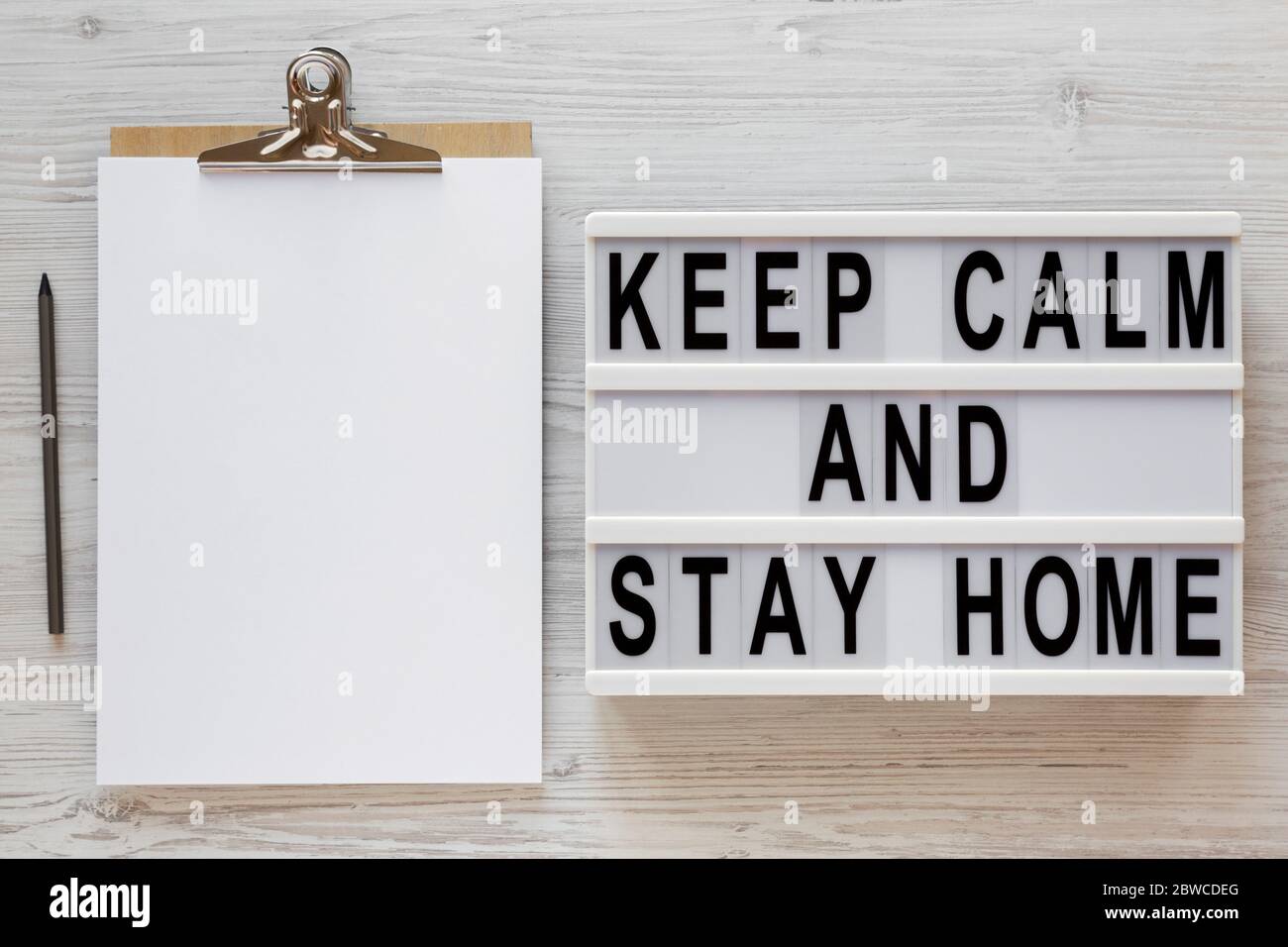 'Keep Calm and Stay Home' words on a lightbox, clipboard with blank ...