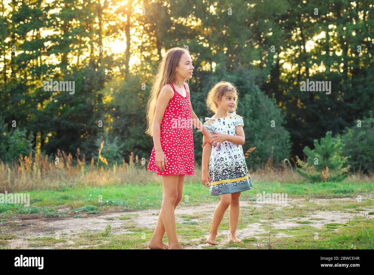 Two pretty little girls embracing and smiling at the countryside. Happy ...
