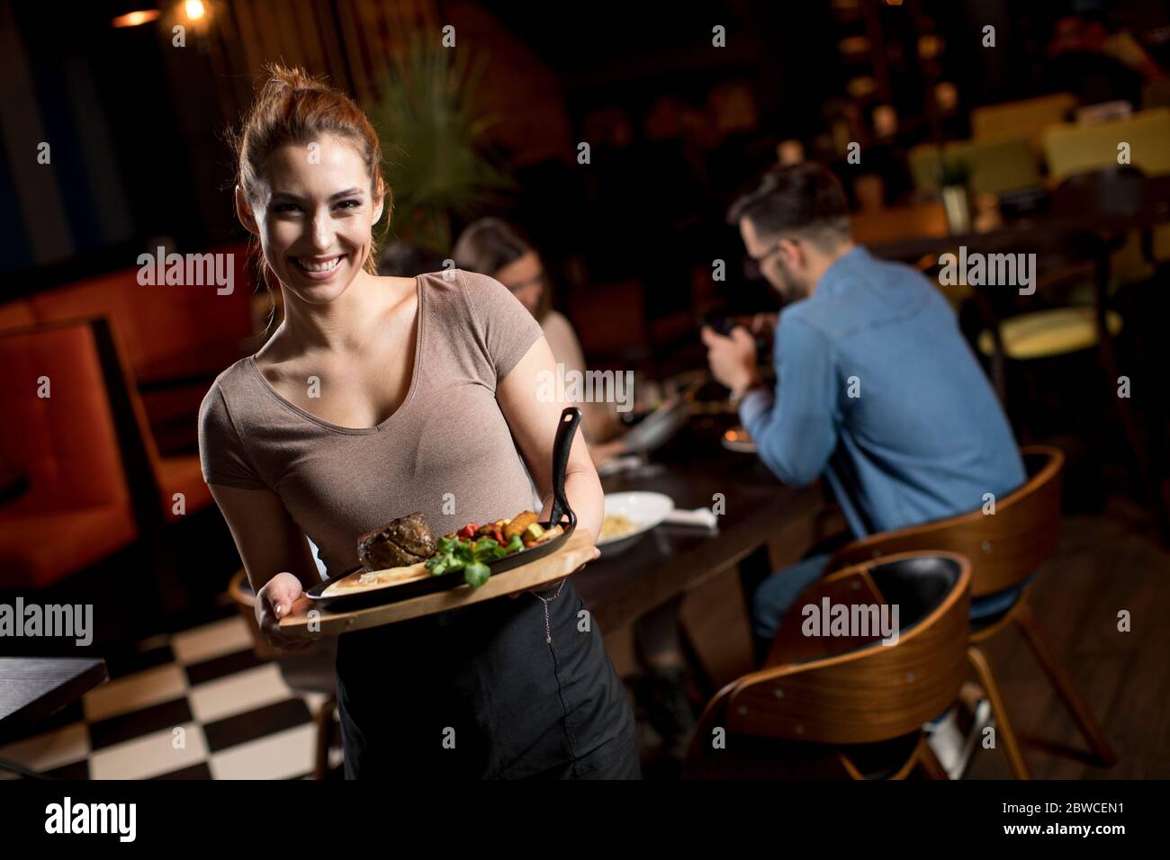 Pretty waiter woman serving group of friends with food in the restaura ...